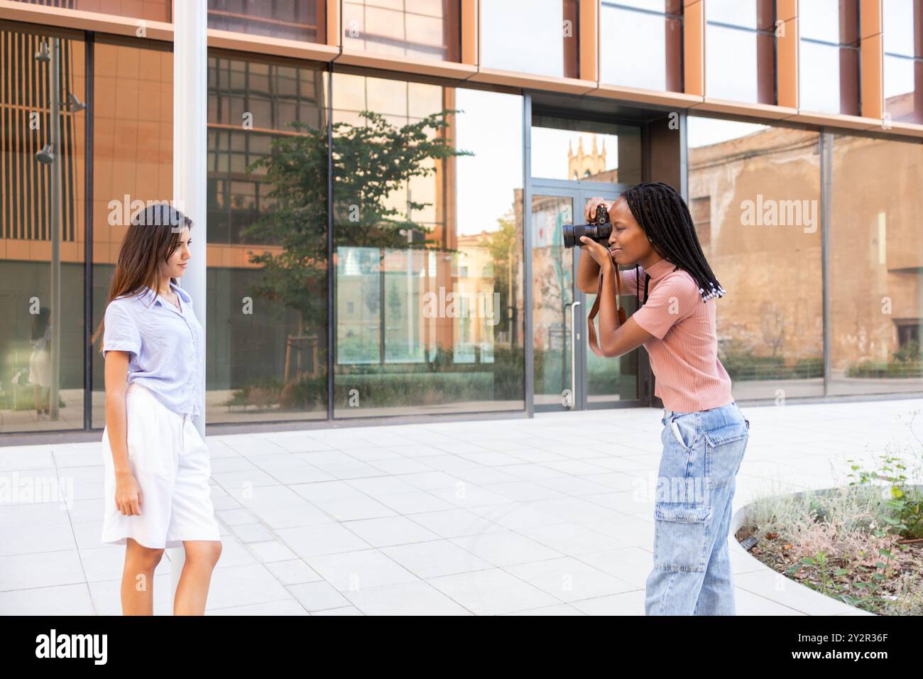 A female college student captures a photograph of her friend, who poses ...