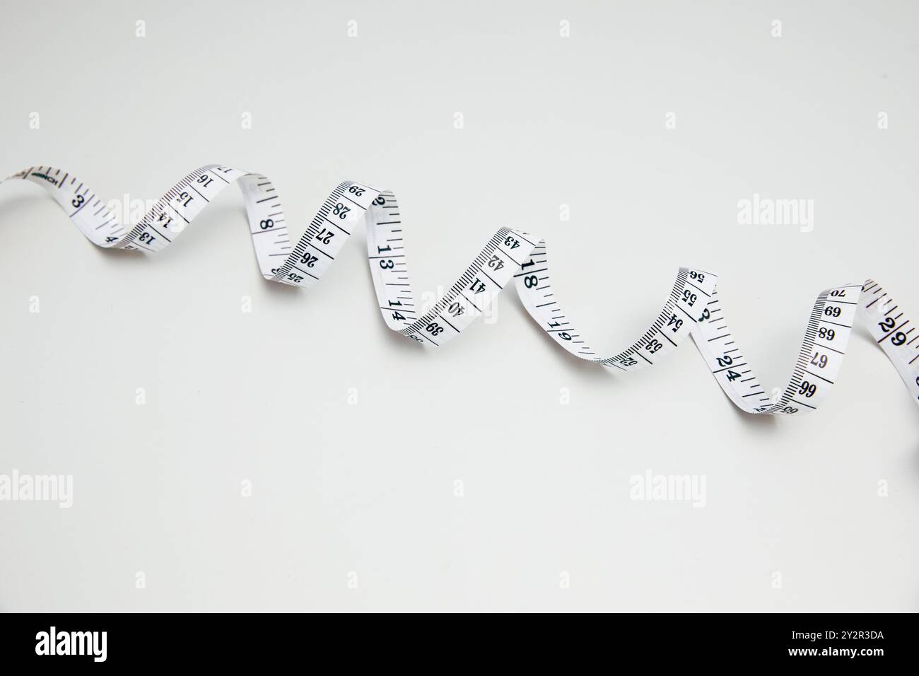 A minimalistic presentation of a white measuring tape curled elegantly ...