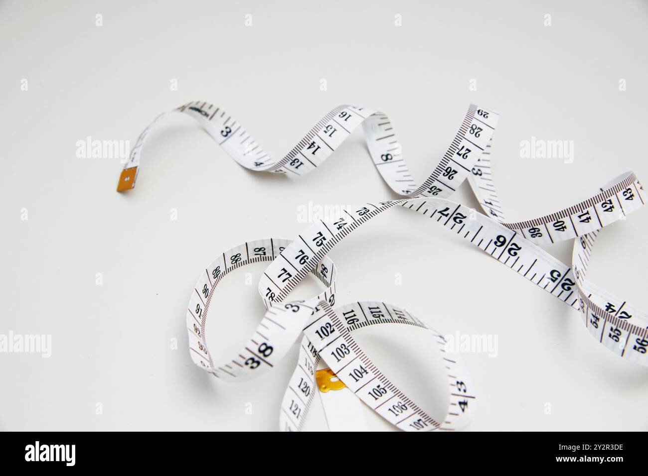 A simple, white measuring scale tape coils in a random, loosely ...