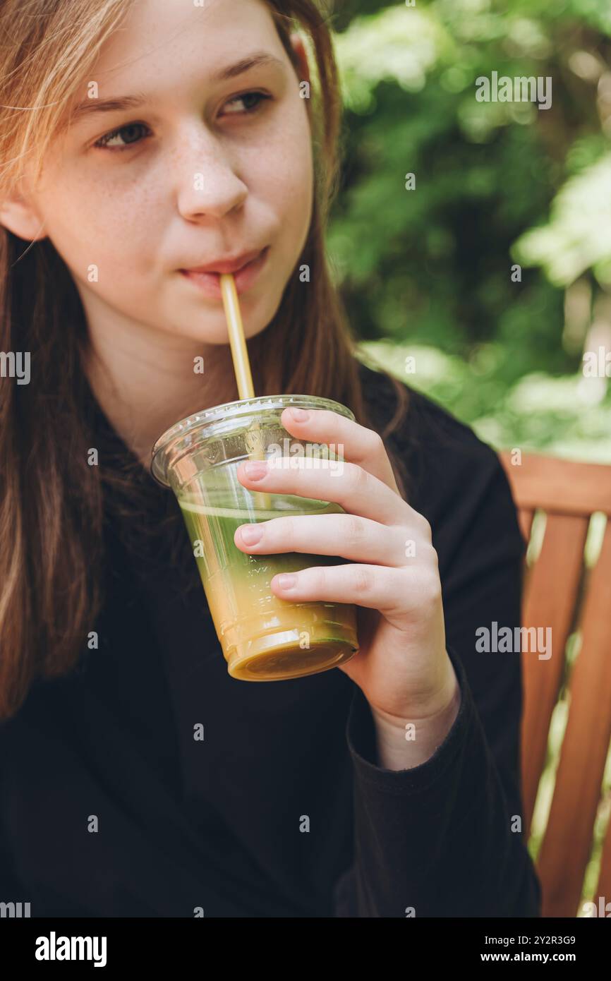 A teenage girl enjoys a refreshing iced matcha ice tea drink in a ...