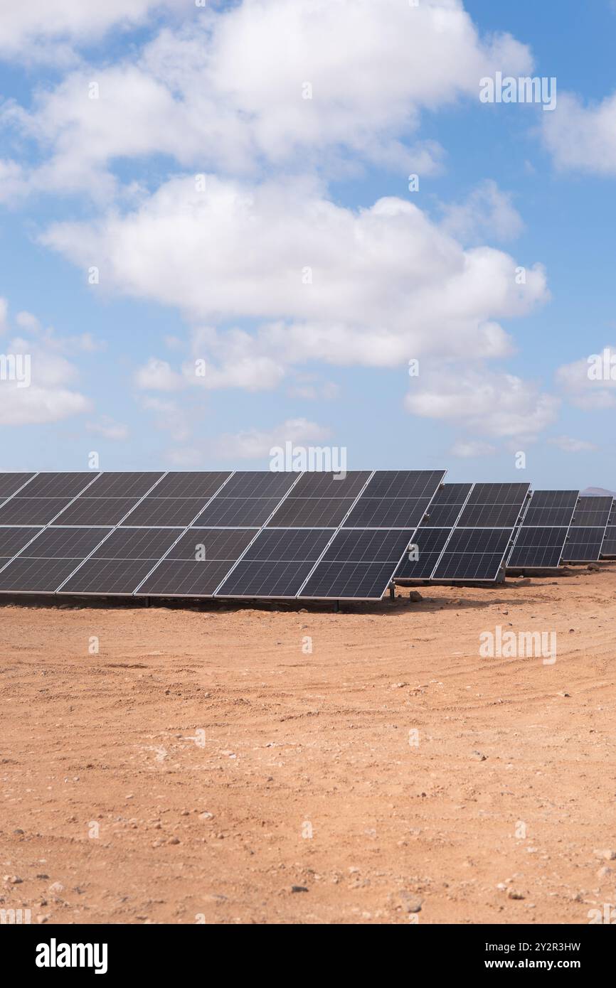 Rows of solar panels capture sunlight in a barren desert, illustrating ...