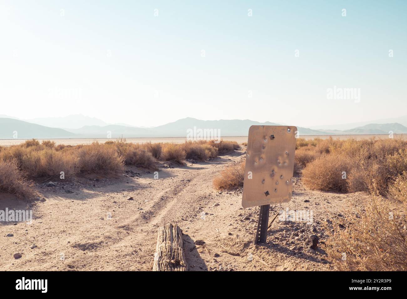 An old, bullet-riddled sign stands amid the vast, sunlit expanse of ...