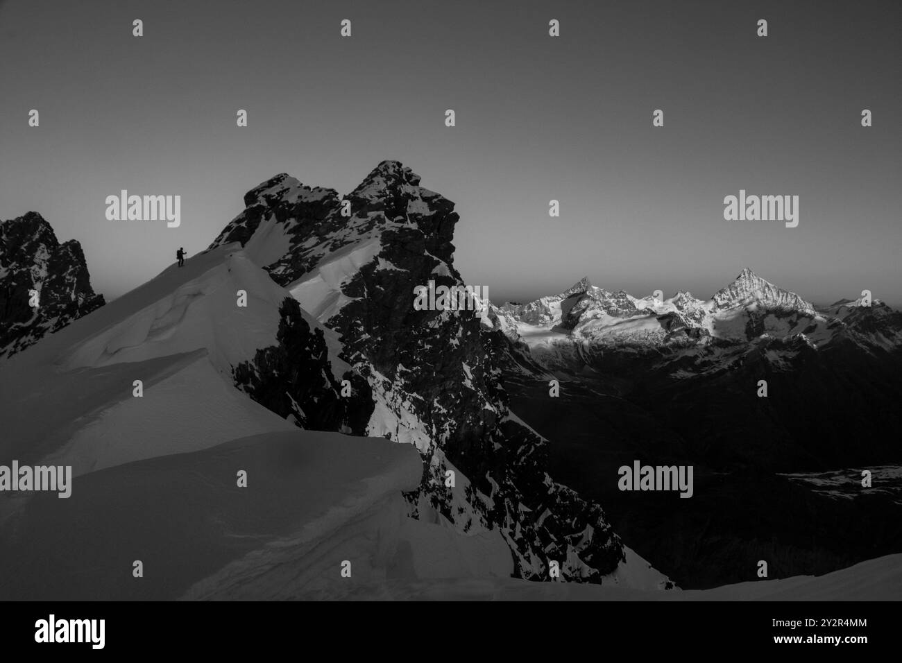 Back view of unrecognizable climber standing on a snowy peak in the ...