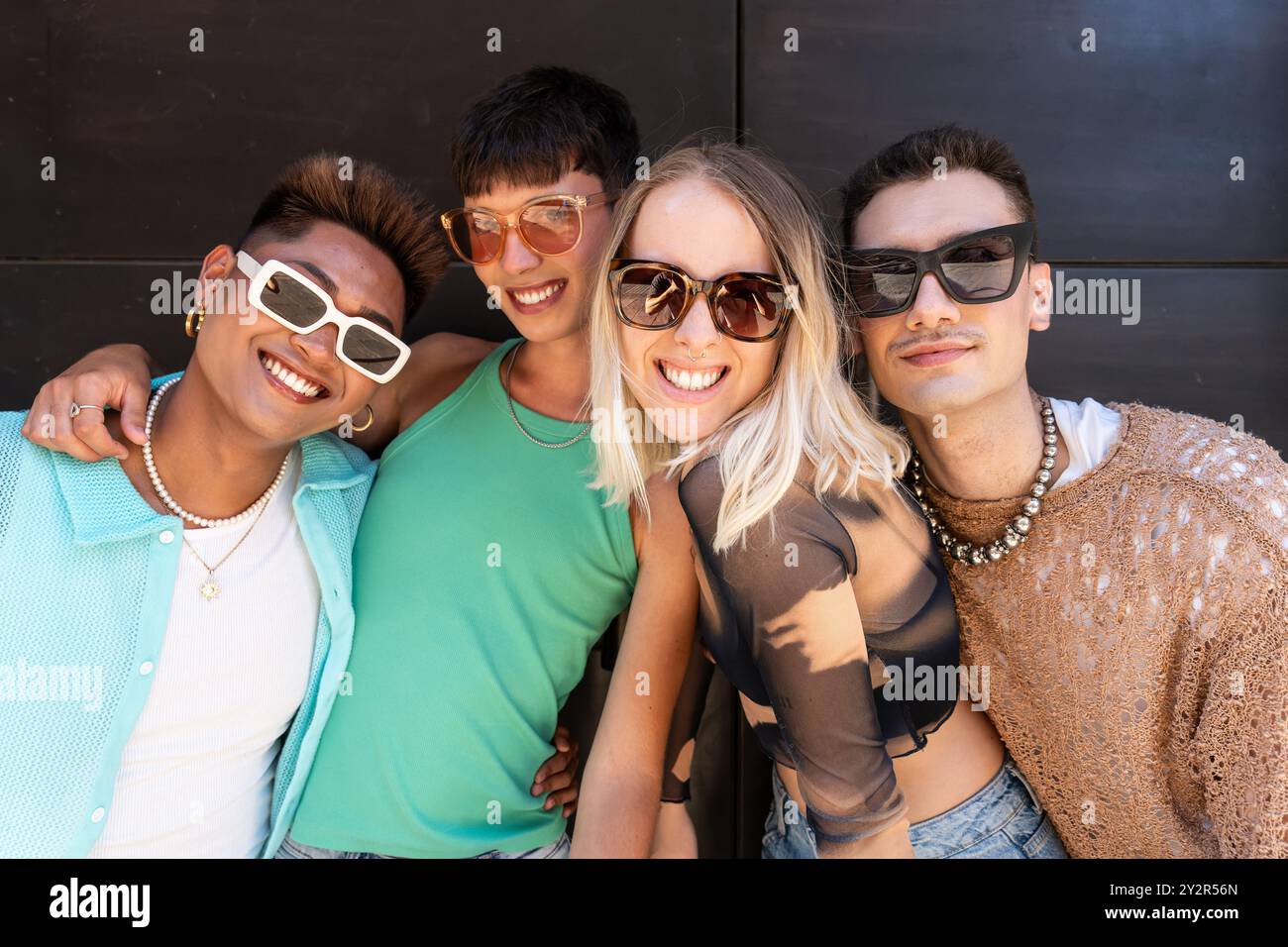 A group of LGBTQIA+ friends stand smiling together, showcasing ...