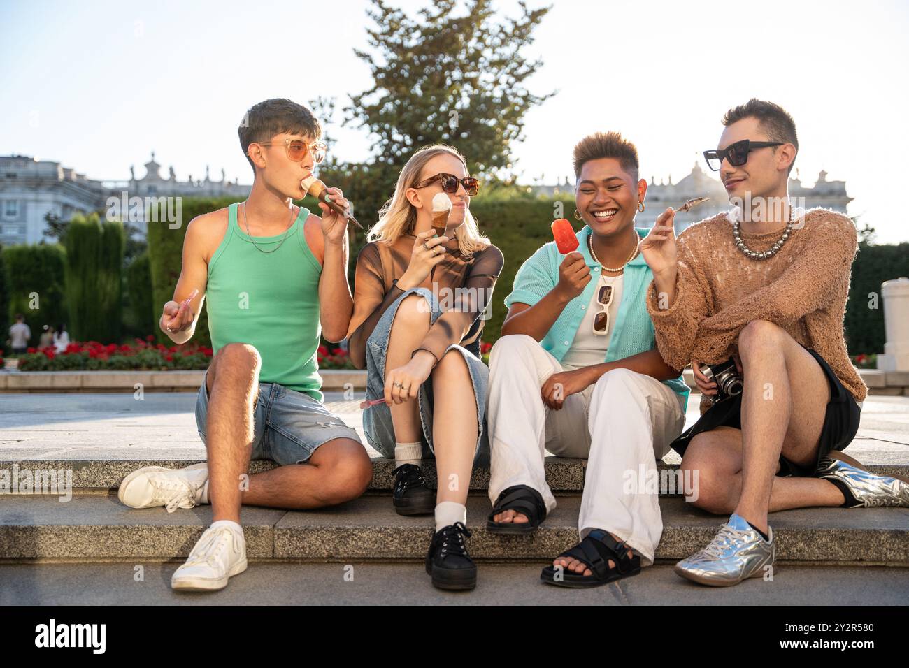 A diverse group of LGBTQIA+ friends laugh and enjoy ice cream together ...