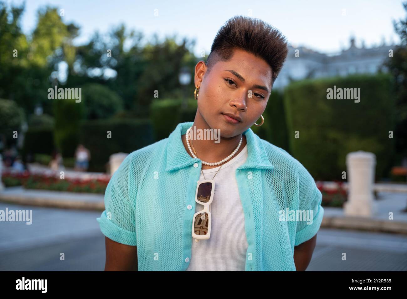 Portrait of non-binary individual posing confidently in an urban park ...