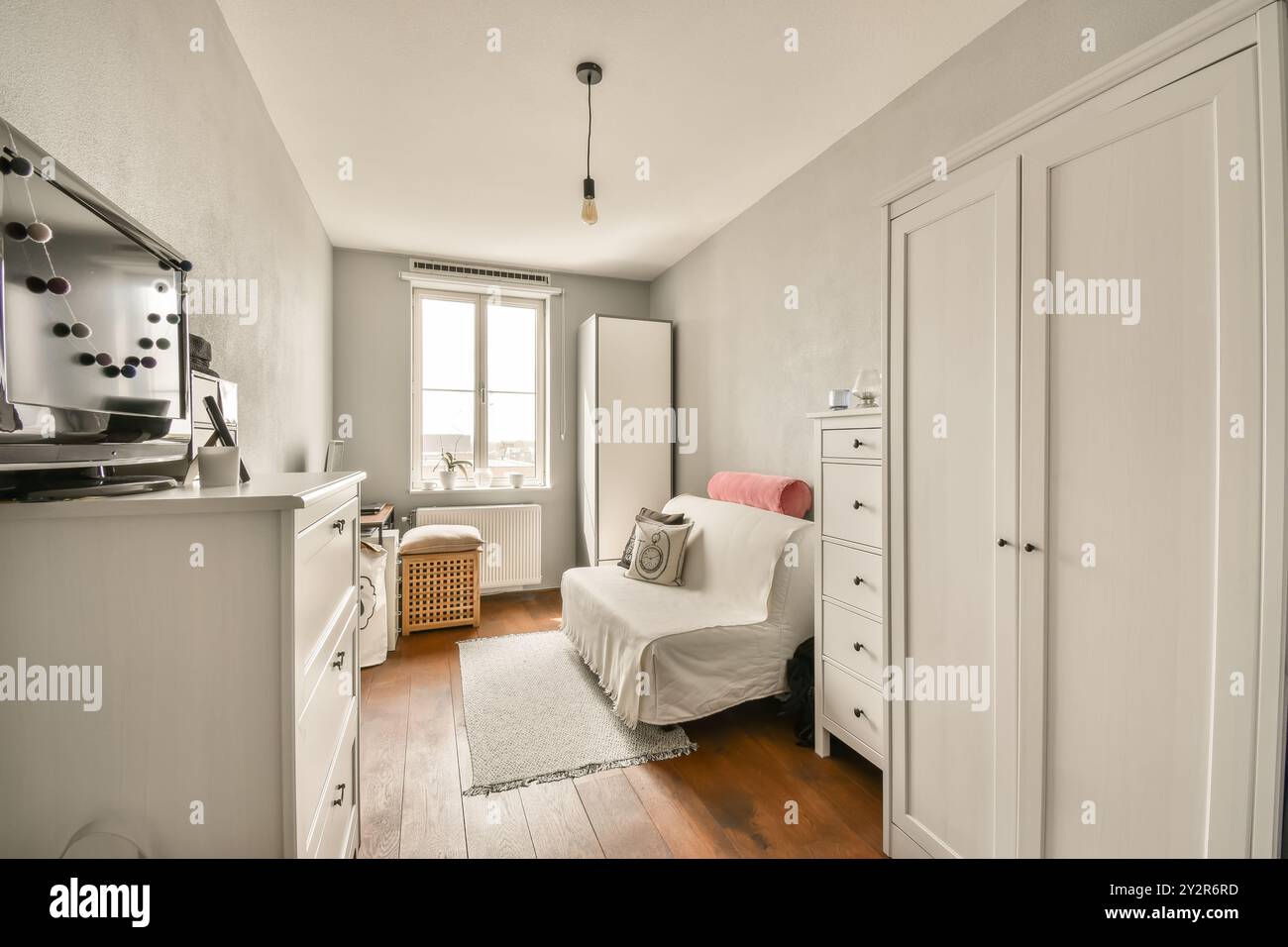 A well-lit small bedroom featuring a comfortable single bed, white ...