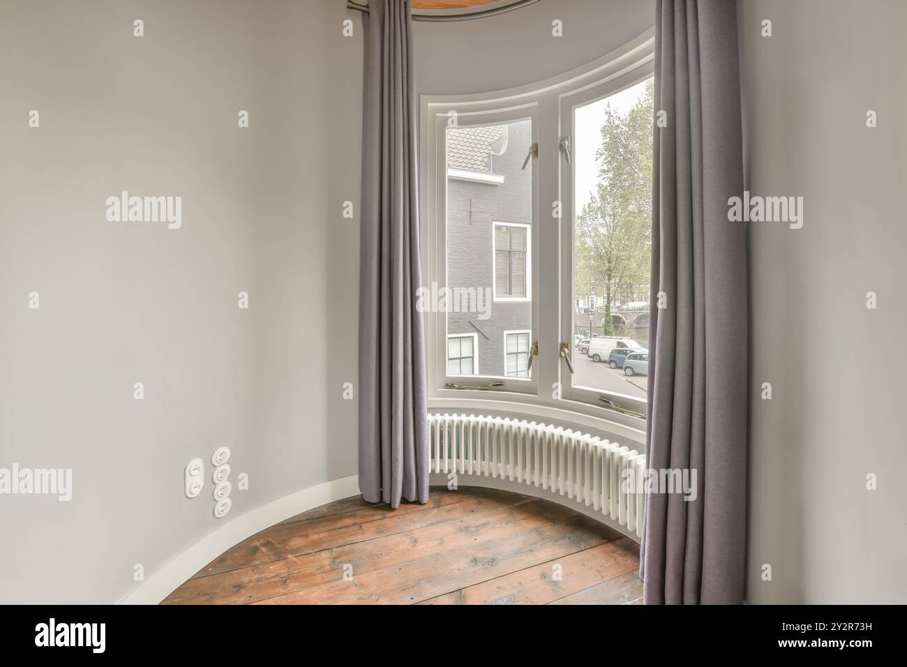 Bay window in an elegant room features classic wooden flooring, grey ...