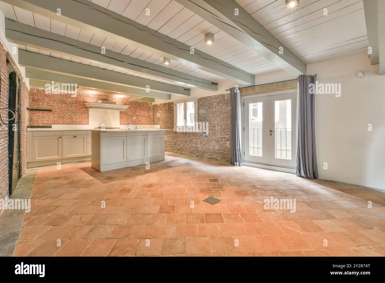 A spacious, renovated kitchen featuring exposed brick walls, a central ...