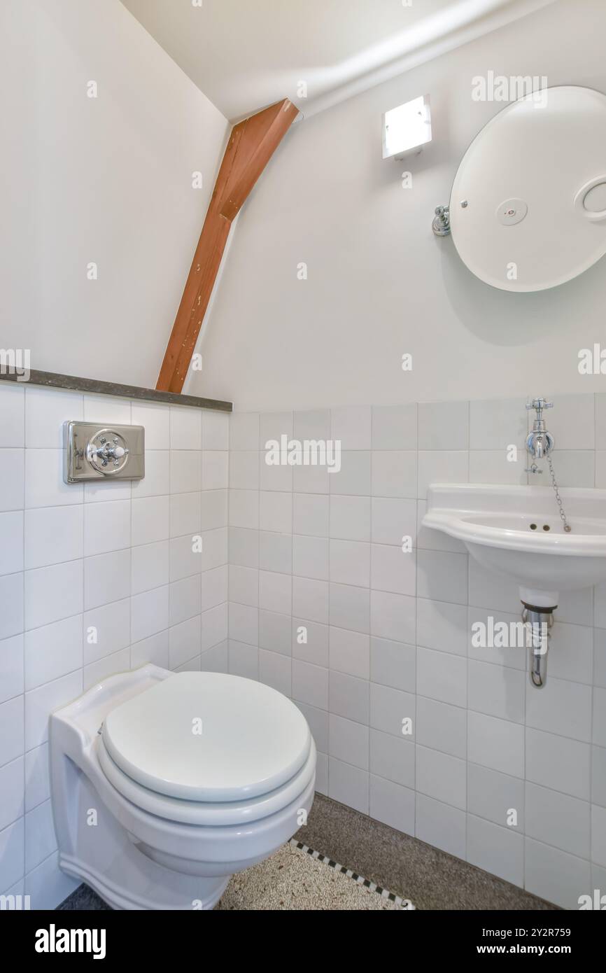A contemporary white tiled bathroom featuring a toilet, sink, and ...