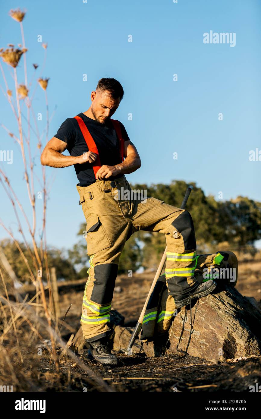 A firefighter is captured adjusting his suspenders, standing by his ...