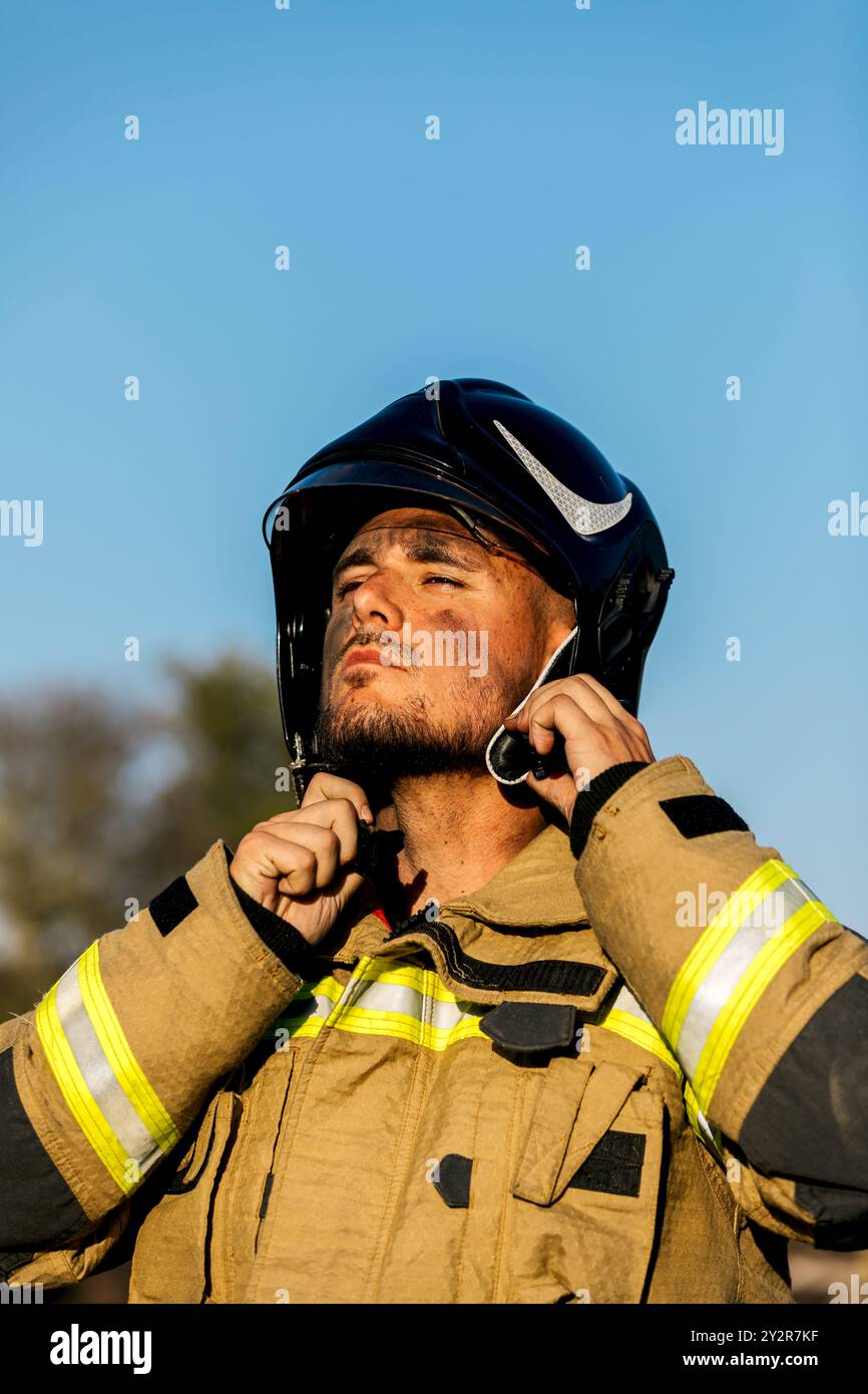A close-up shot of a focused firefighter adjusting his helmet in a ...