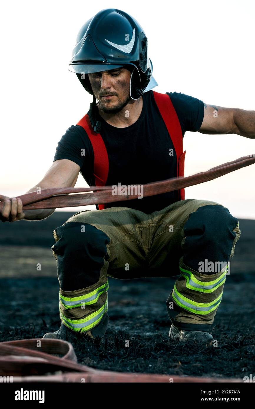 Captured in the fading light, a focused firefighter in gear manages a ...