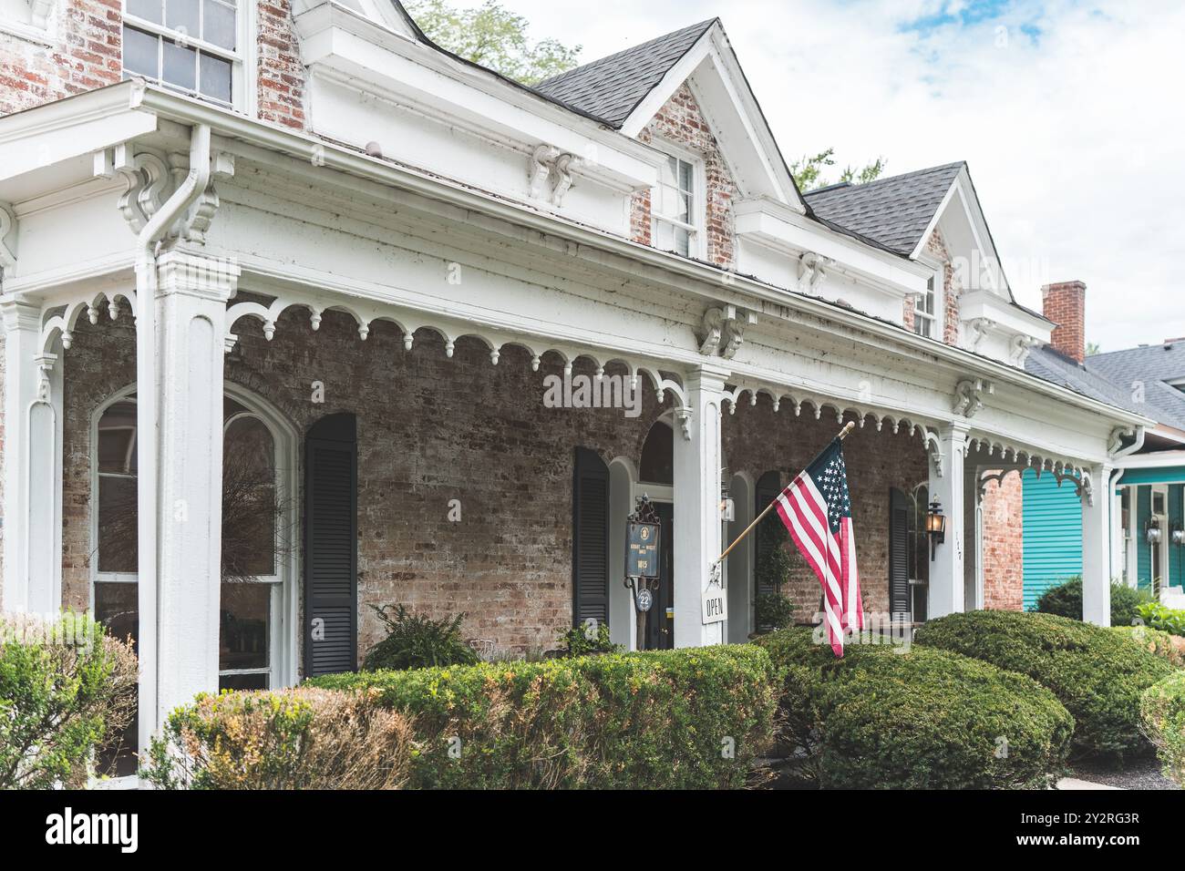 A charming brick house with a white porch and an American flag ...