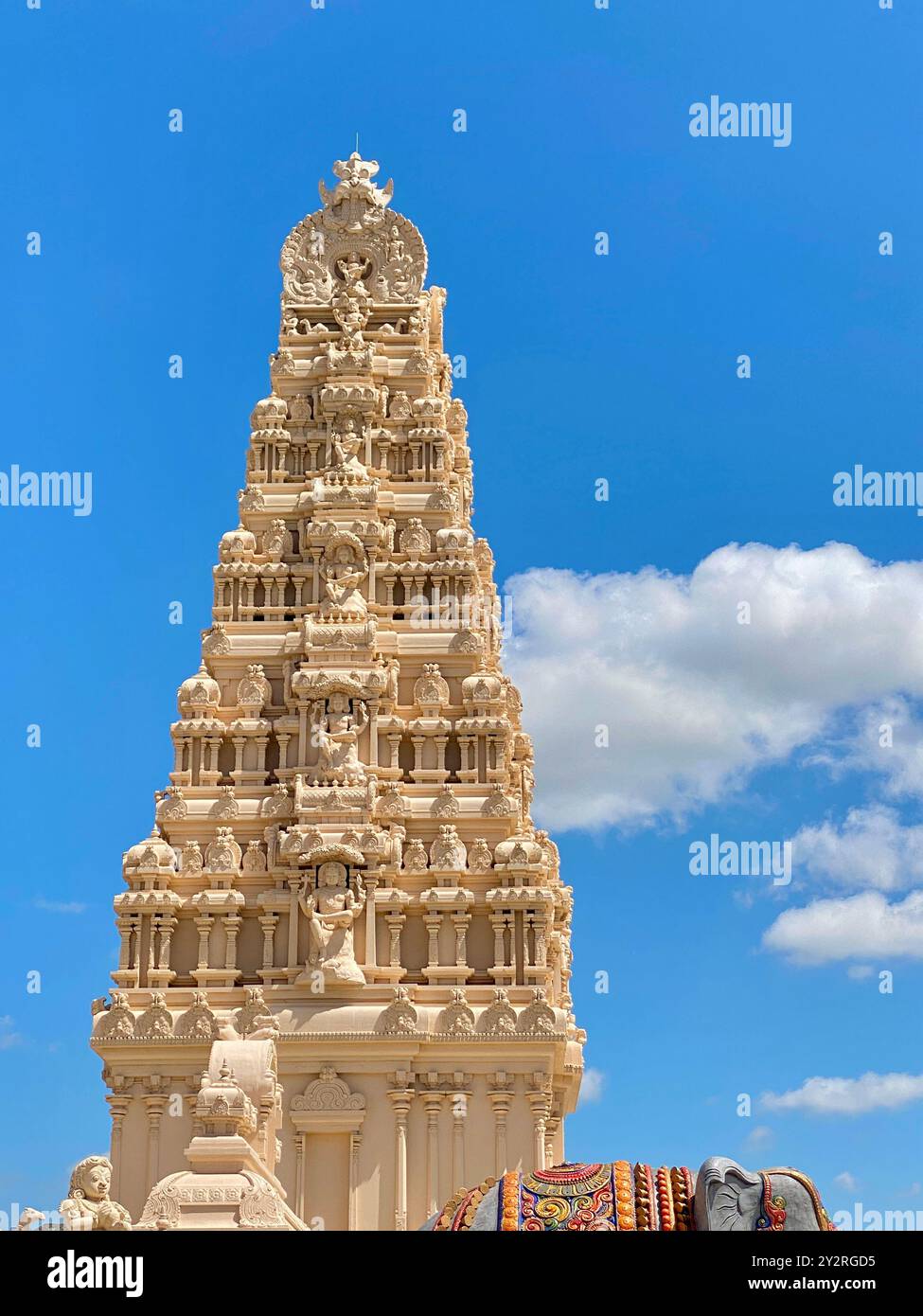 A detailed view of a Hindu temple tower against a clear blue sky with ...