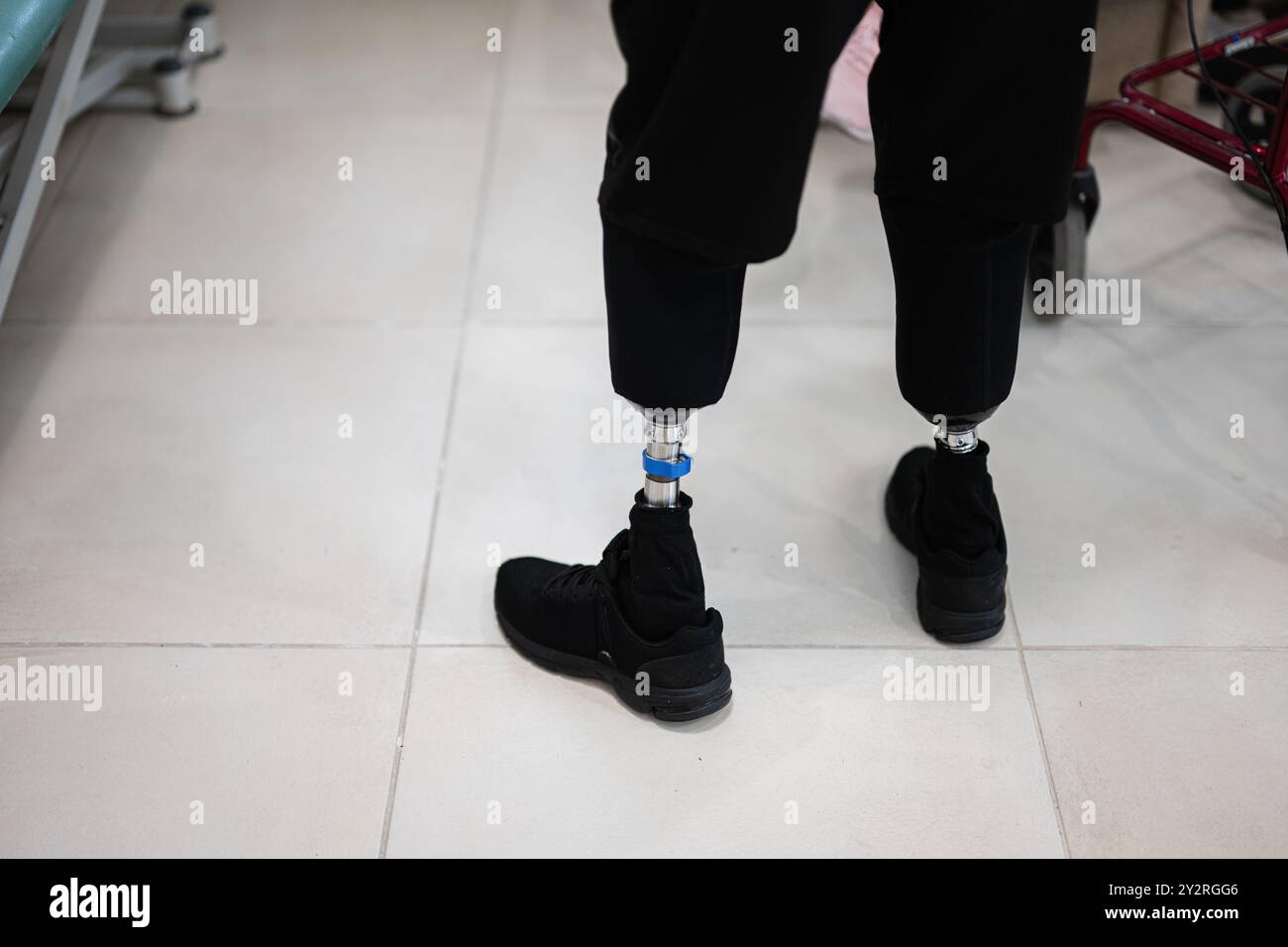 A person is shown walking using prosthetic legs in a rehabilitation ...
