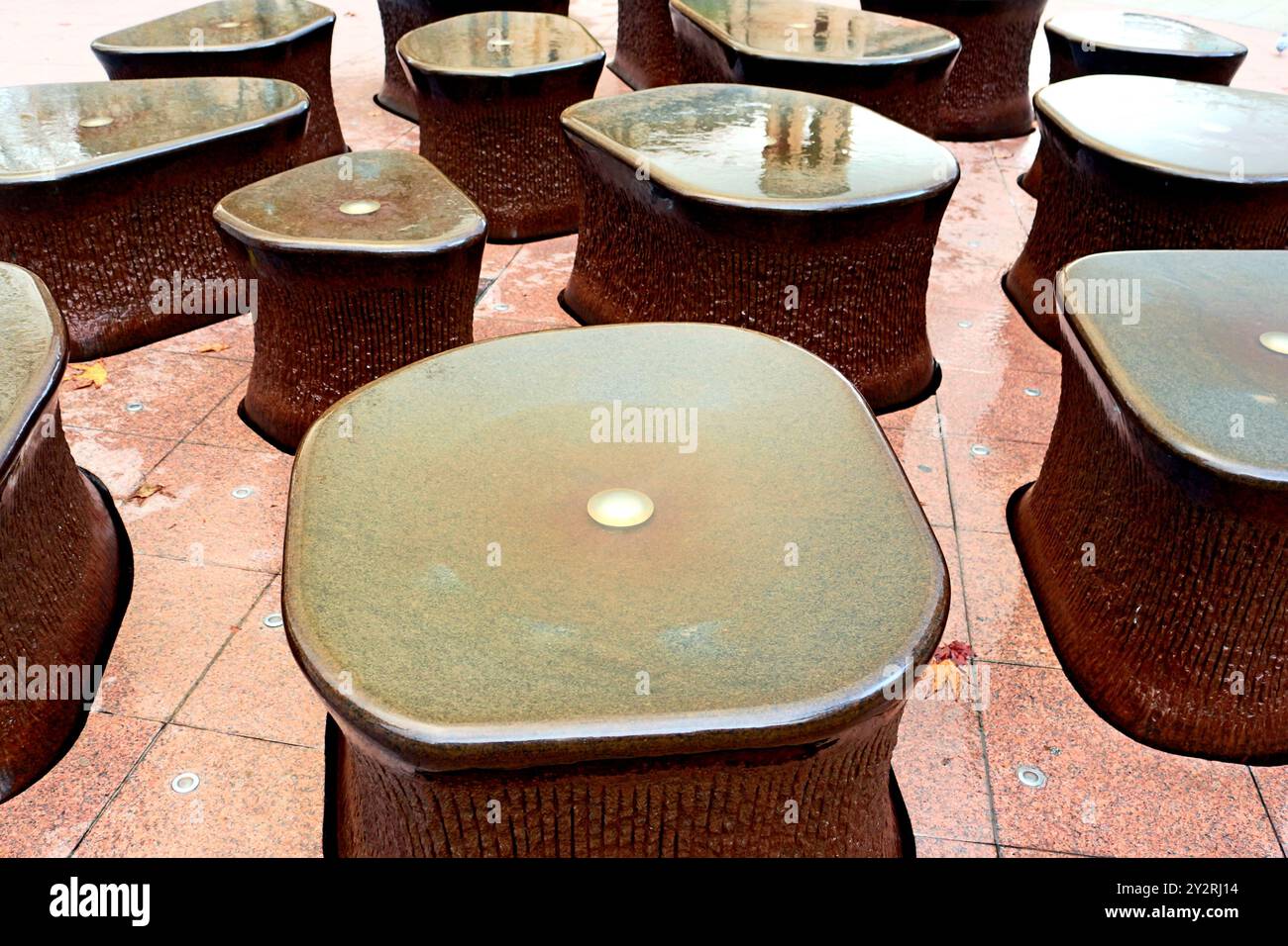 Unique stone seats arranged in an outdoor setting with a wet surface ...