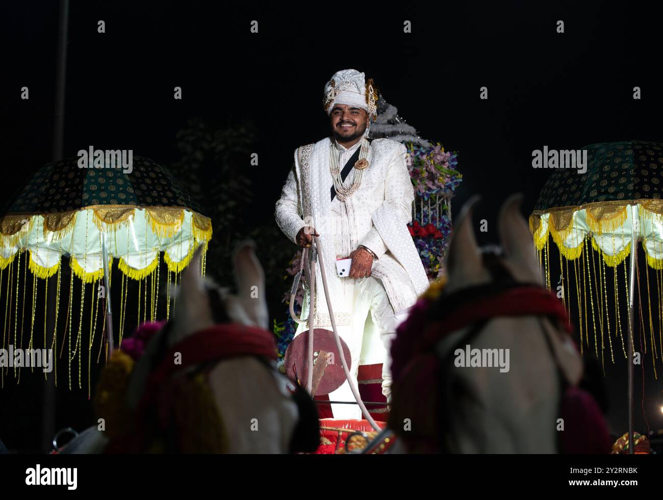 A groom dressed in traditional attire riding a decorated horse carriage ...