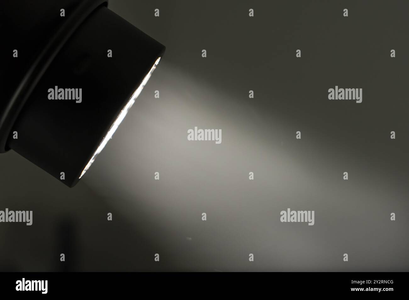 In a dark room, a directed beam of light. The beam of light is visible ...