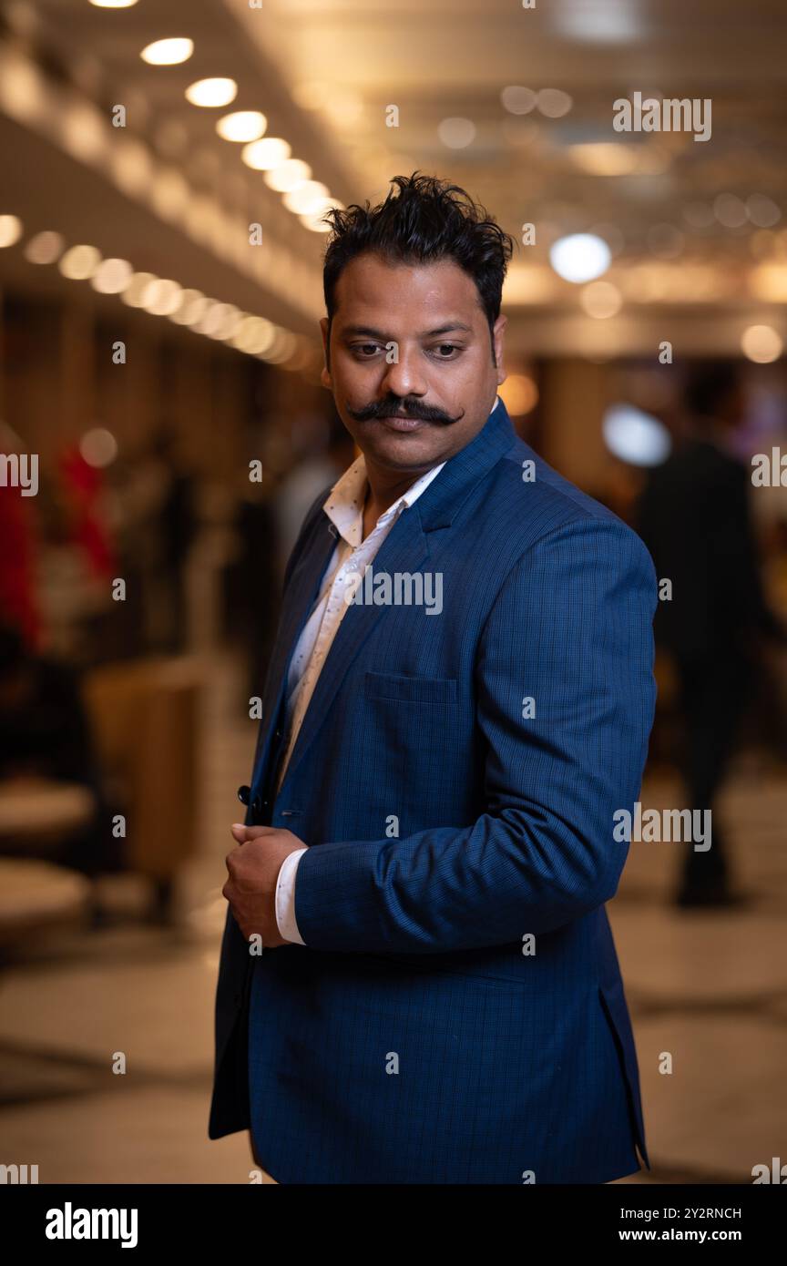 Portrait of a man in a blue suit with a mustache, standing in a well ...