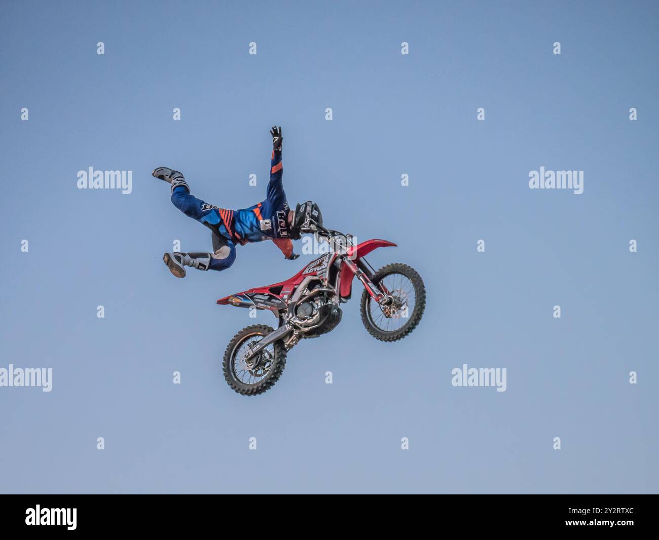 A motocross rider performing an aerial stunt on a red dirt bike against ...