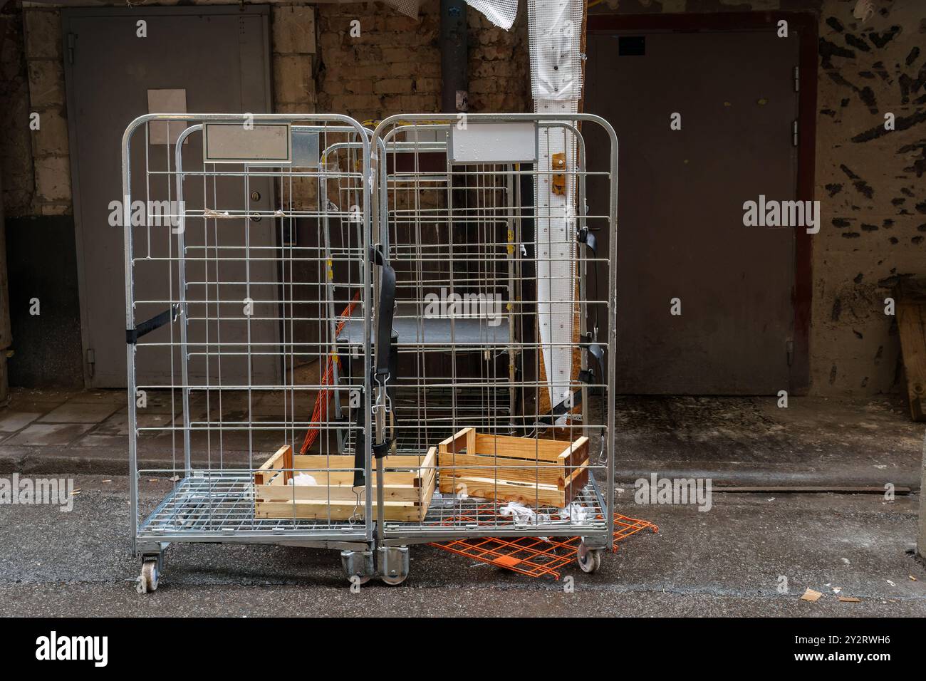 Two metal trolleys with wooden boxes in front of a building entrance ...