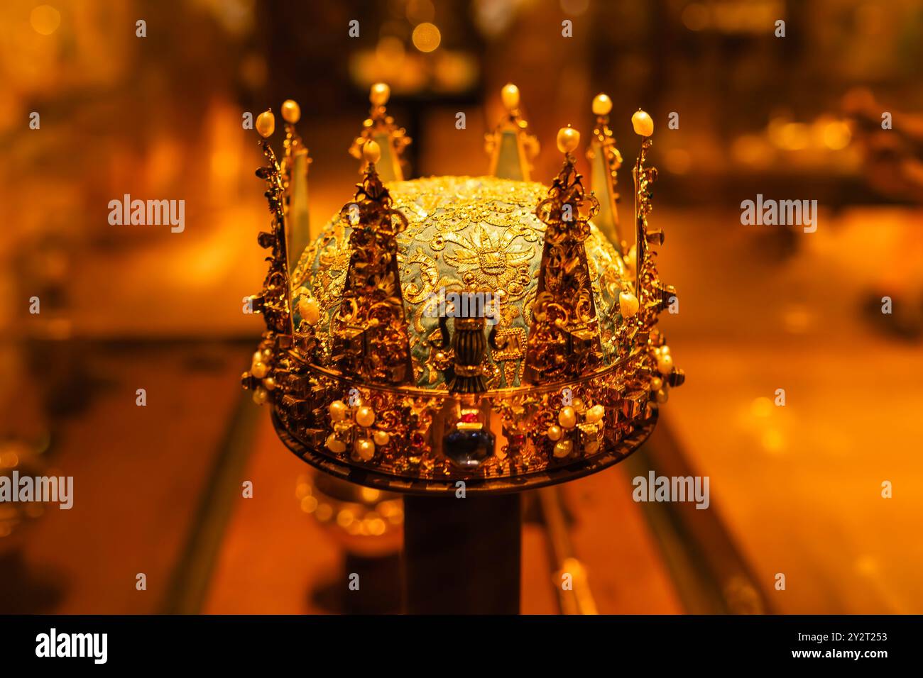 An ornate golden crown encrusted with jewels displayed in a museum ...