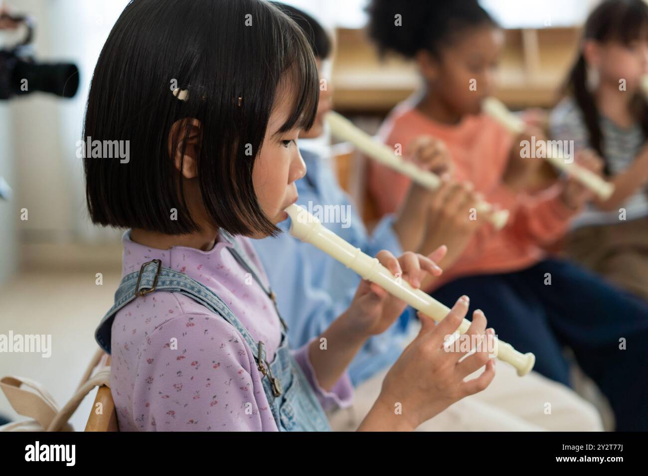 Diverse elementary students practice flutes in vibrant music classroom ...