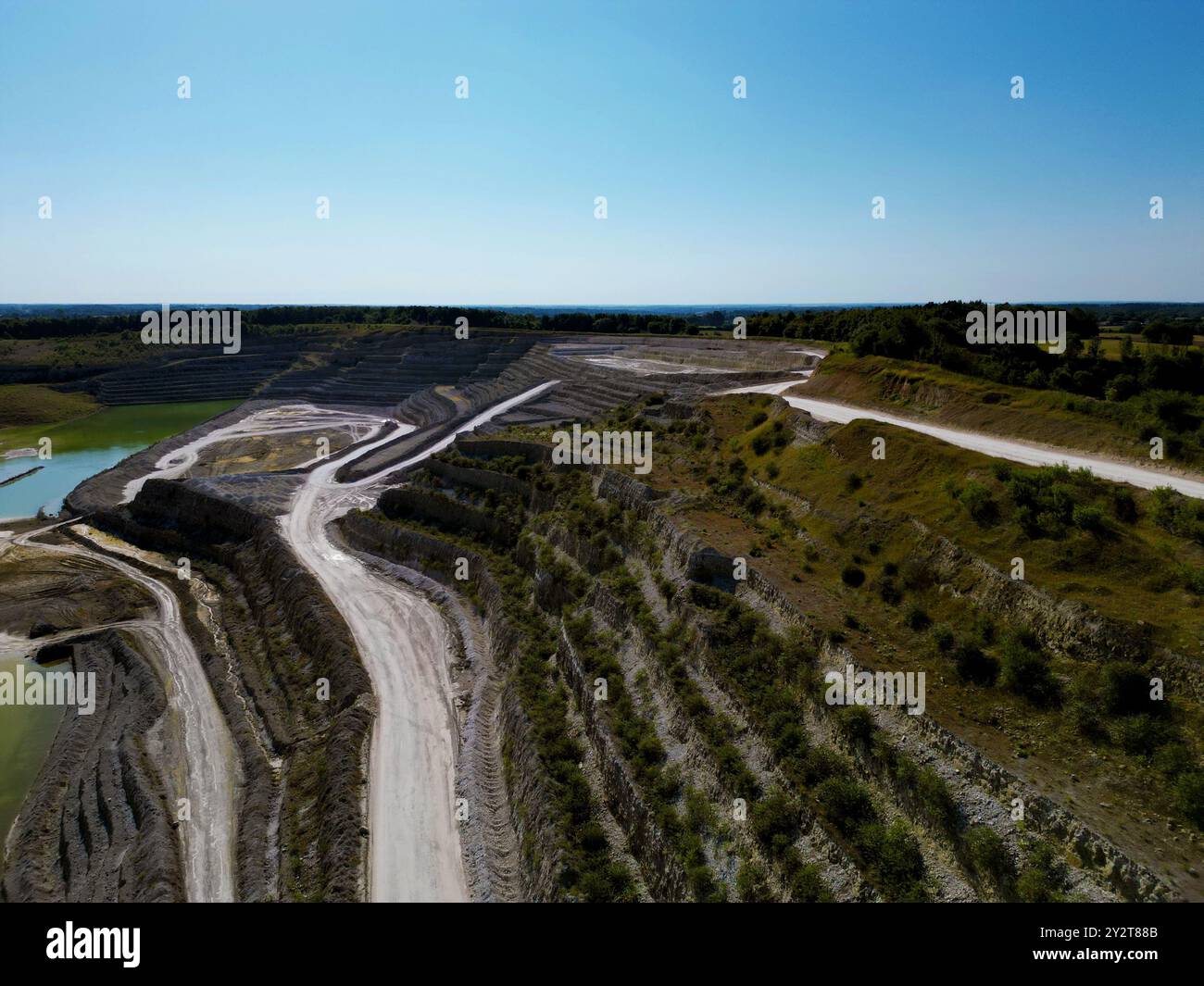 Aerial view of an open-pit mine with winding roads and a clear blue sky ...