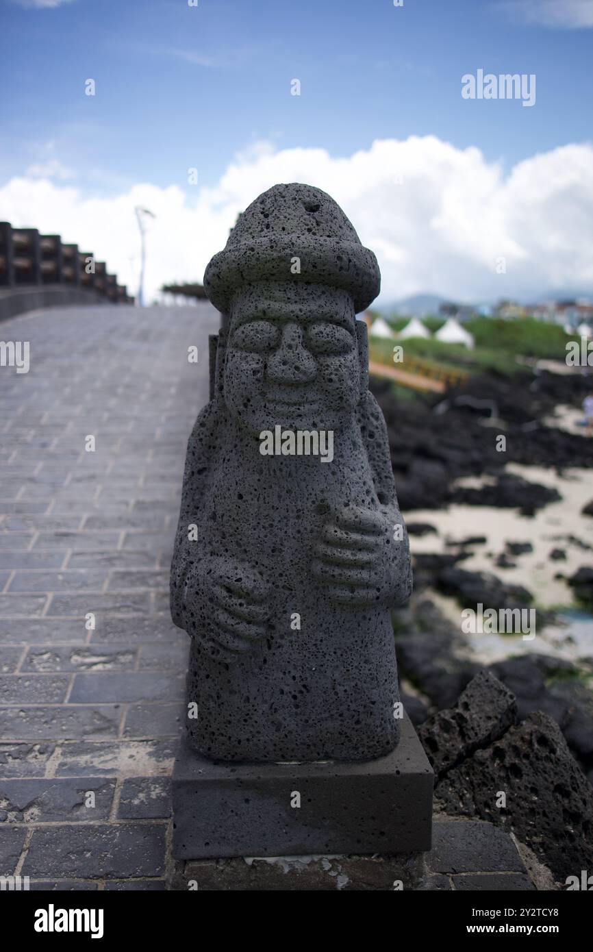A traditional Dol Hareubang statue on a stone pathway with a scenic ...