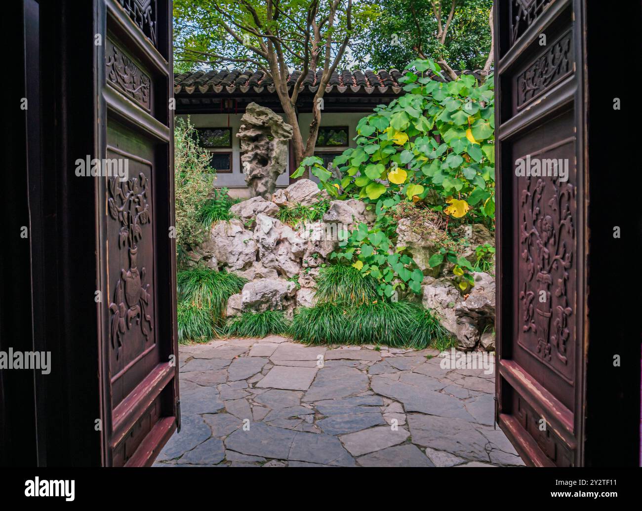 A serene garden view through ornate wooden doors in a traditional ...