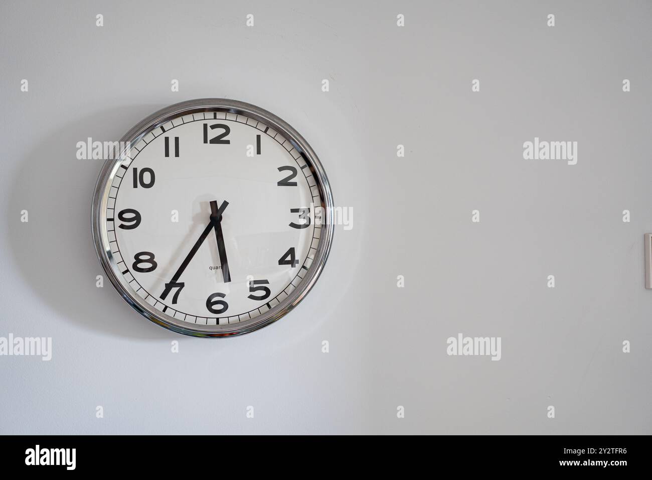 Analog clock on a minimalist wall with clear numbers and hands showing ...