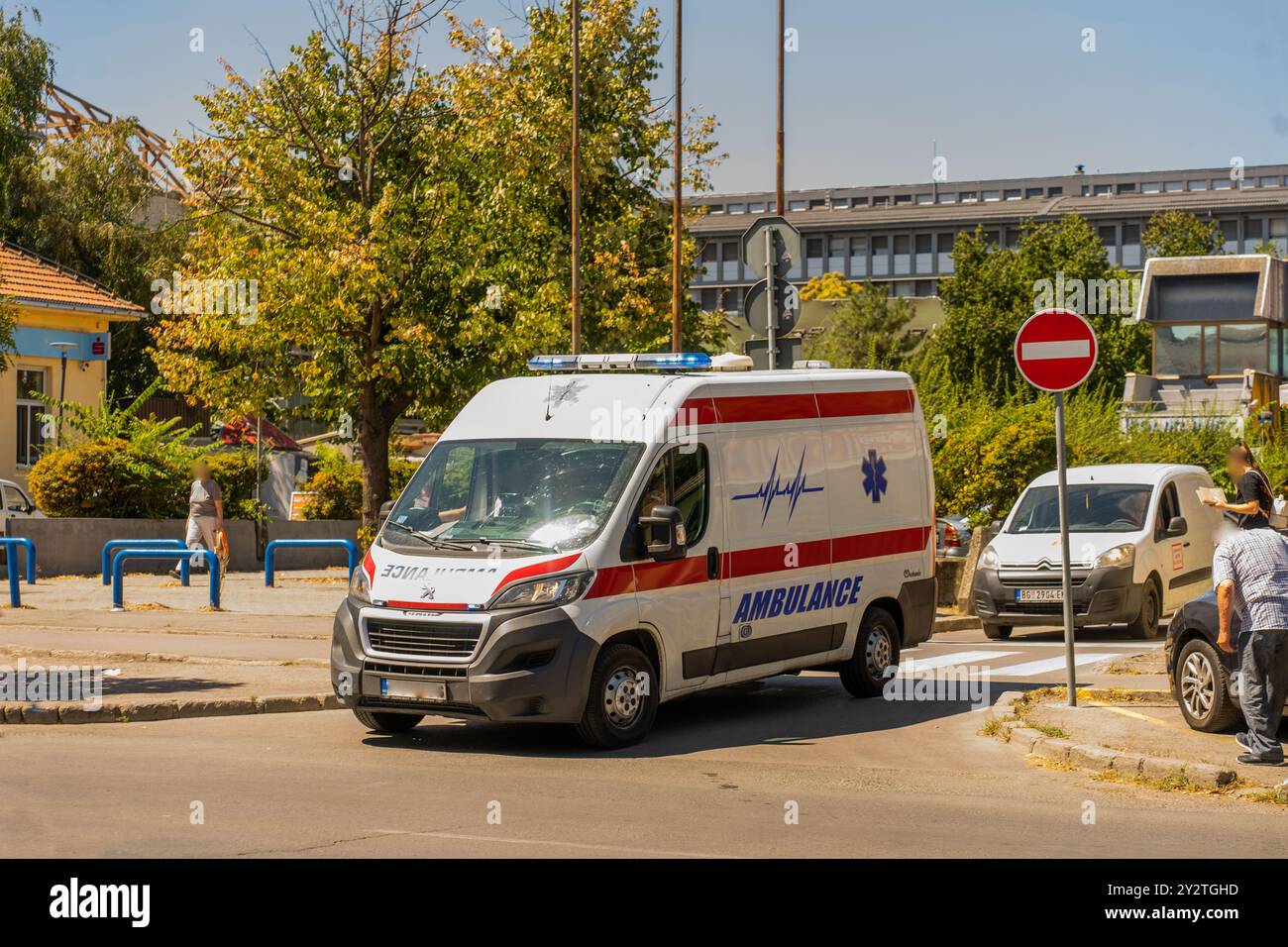 An ambulance vehicle driving on a city street with buildings in the ...
