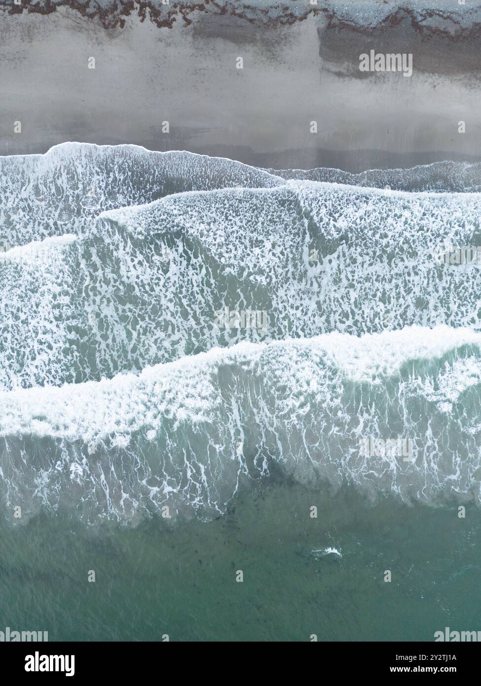 Aerial view of ocean waves crashing onto the shore creating beautiful ...
