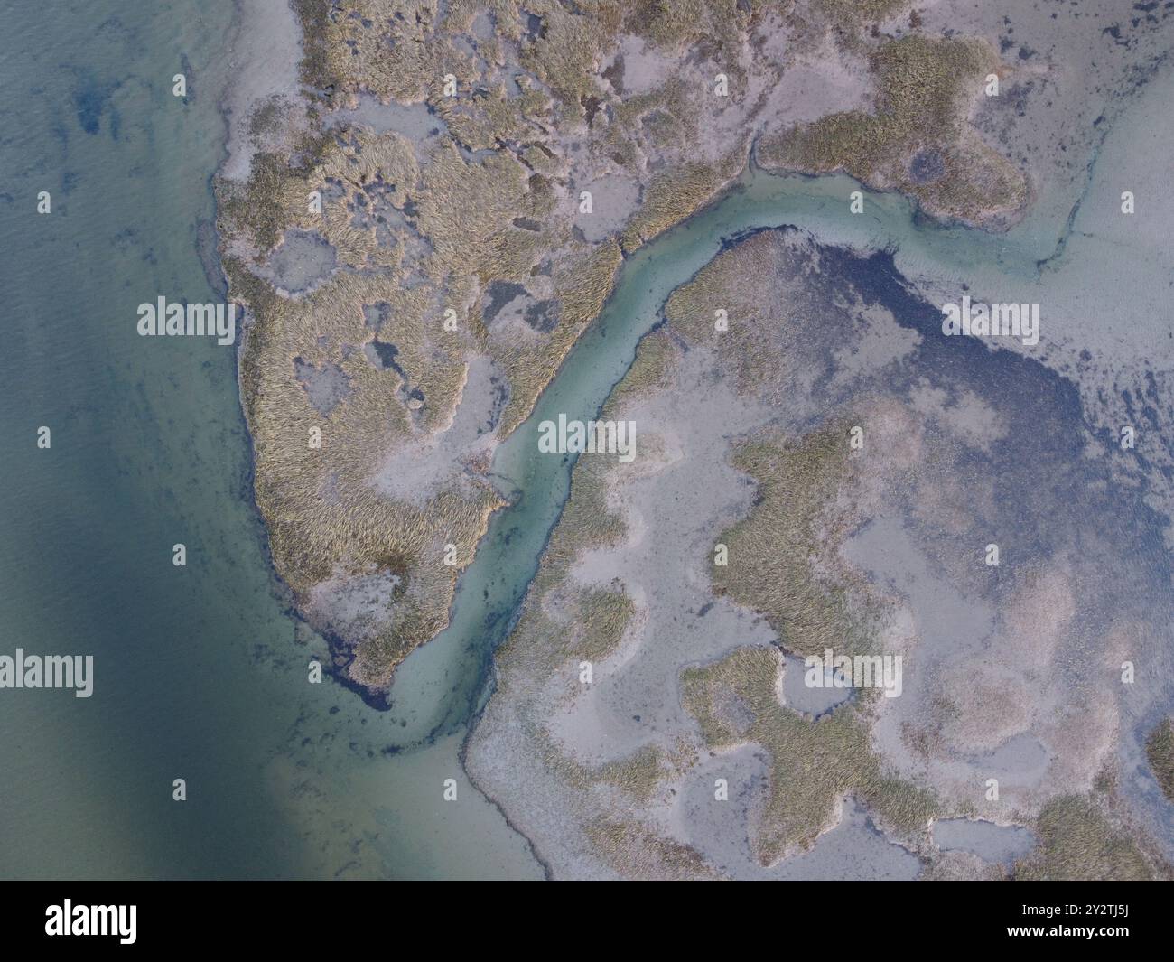 Aerial view of a marshland with patches of grass and water creating a ...