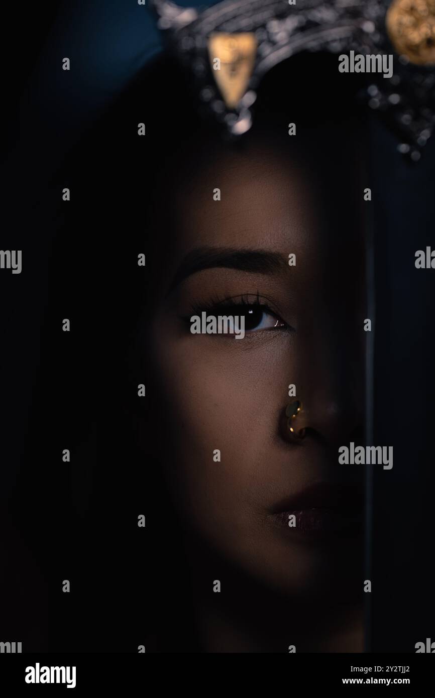 A close-up vertical portrait of Southeast Asian woman's shadowed face ...