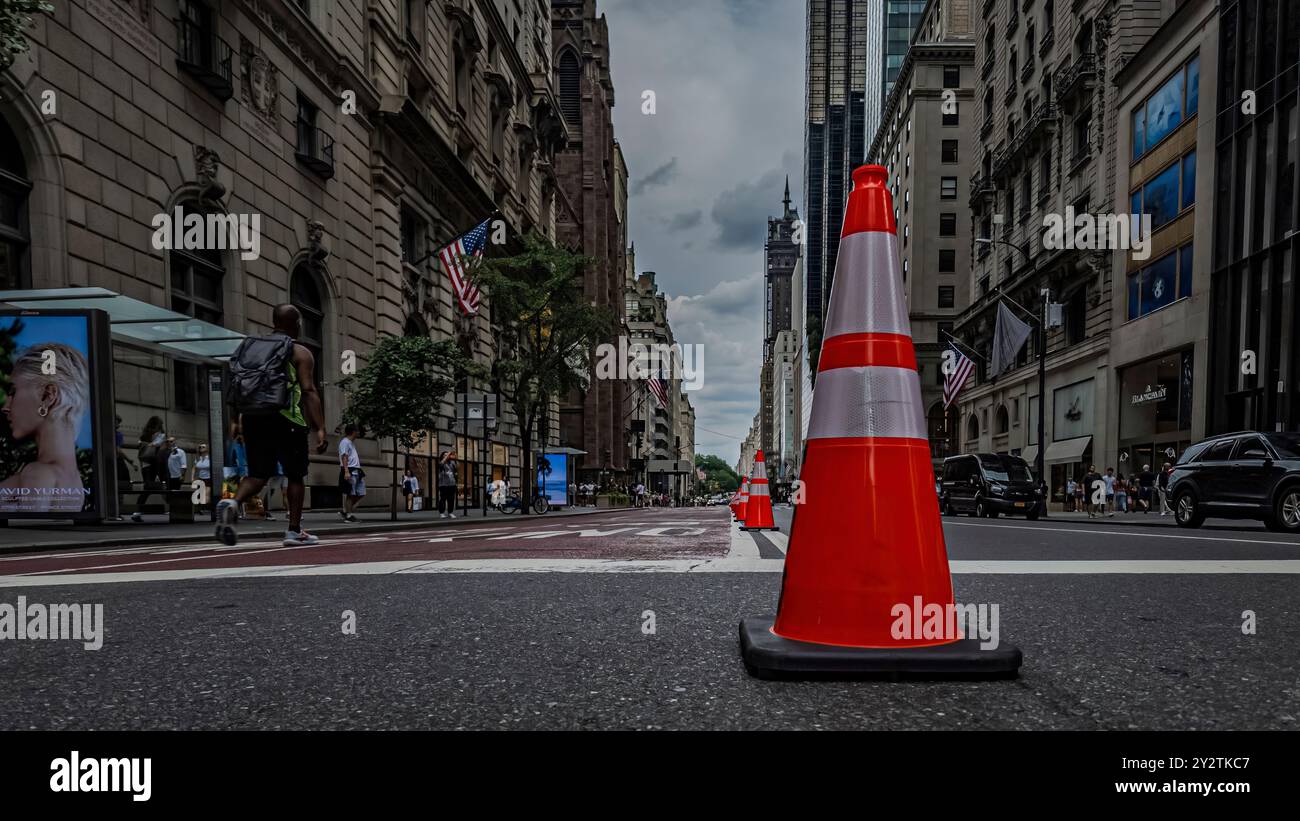 A closeup view orange traffic cone with urban buildings in the ...