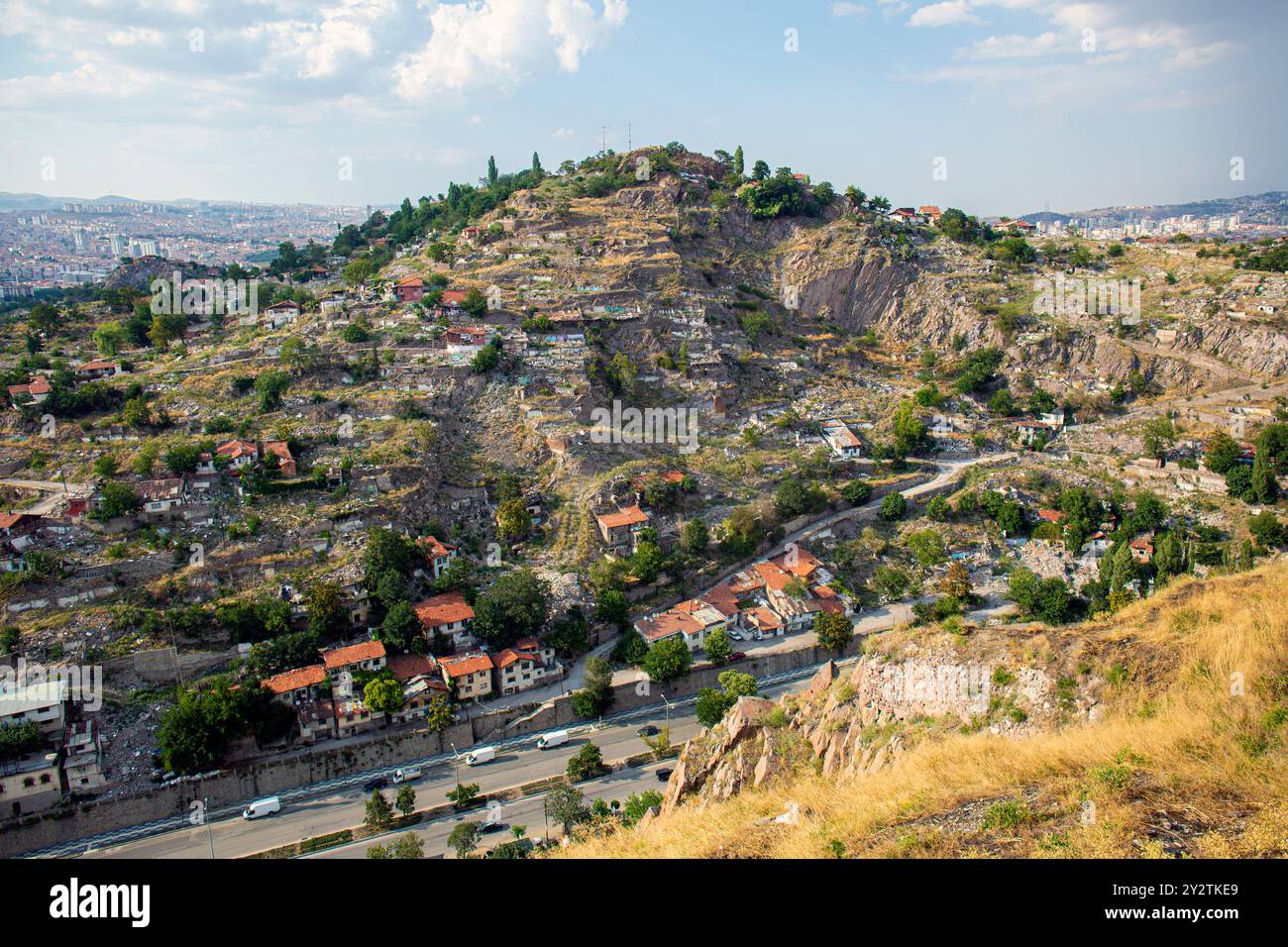 Hillside town sprawls over rocky terrain, red-roofed houses dotting the ...