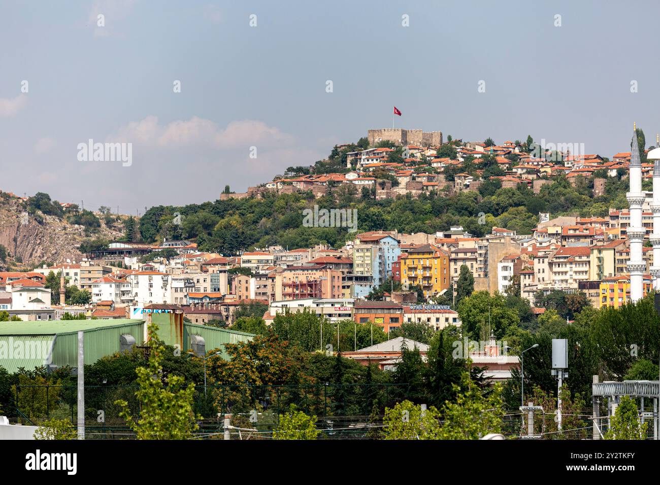 Colorful hillside city with ancient castle and red flag atop, minarets ...
