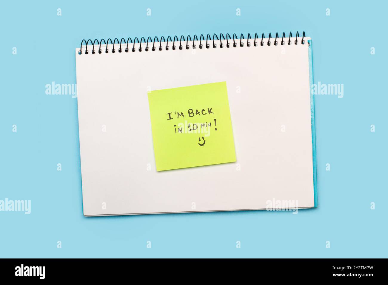 A white blank notepad with a sticky paper with Im back in 10 minutes ...