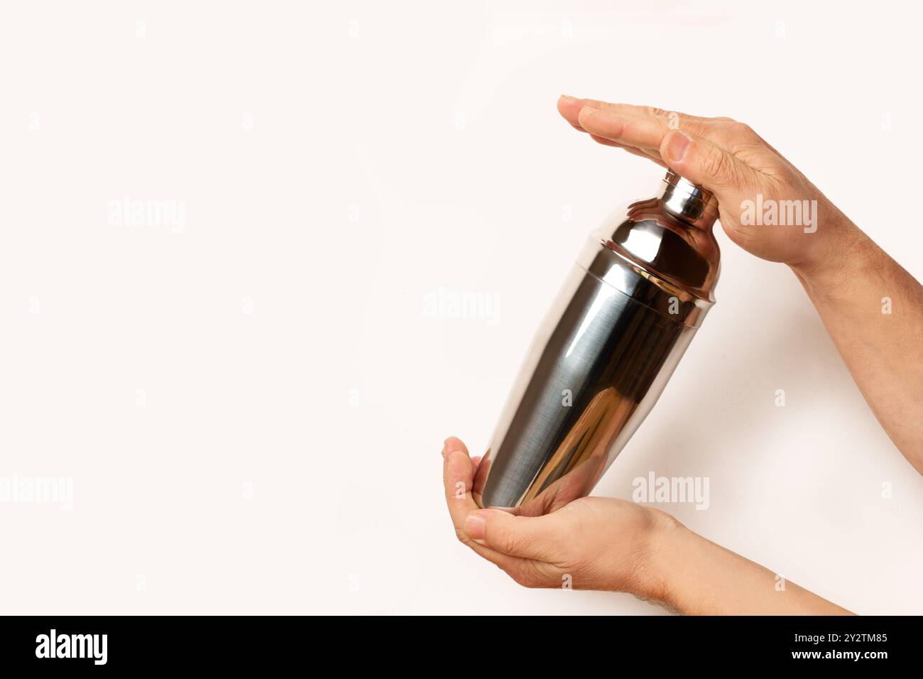 Man hands shaking a cocktail shaker on a white background with copy ...