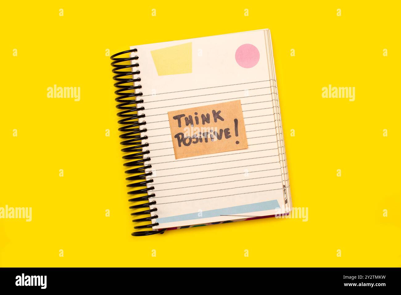A spiral notepad with a sticky paper with Think Positive short phrase ...