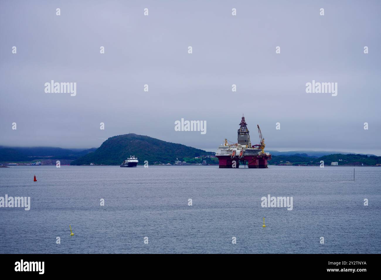 An offshore oil rig and a ship in the ocean with a mountainous ...