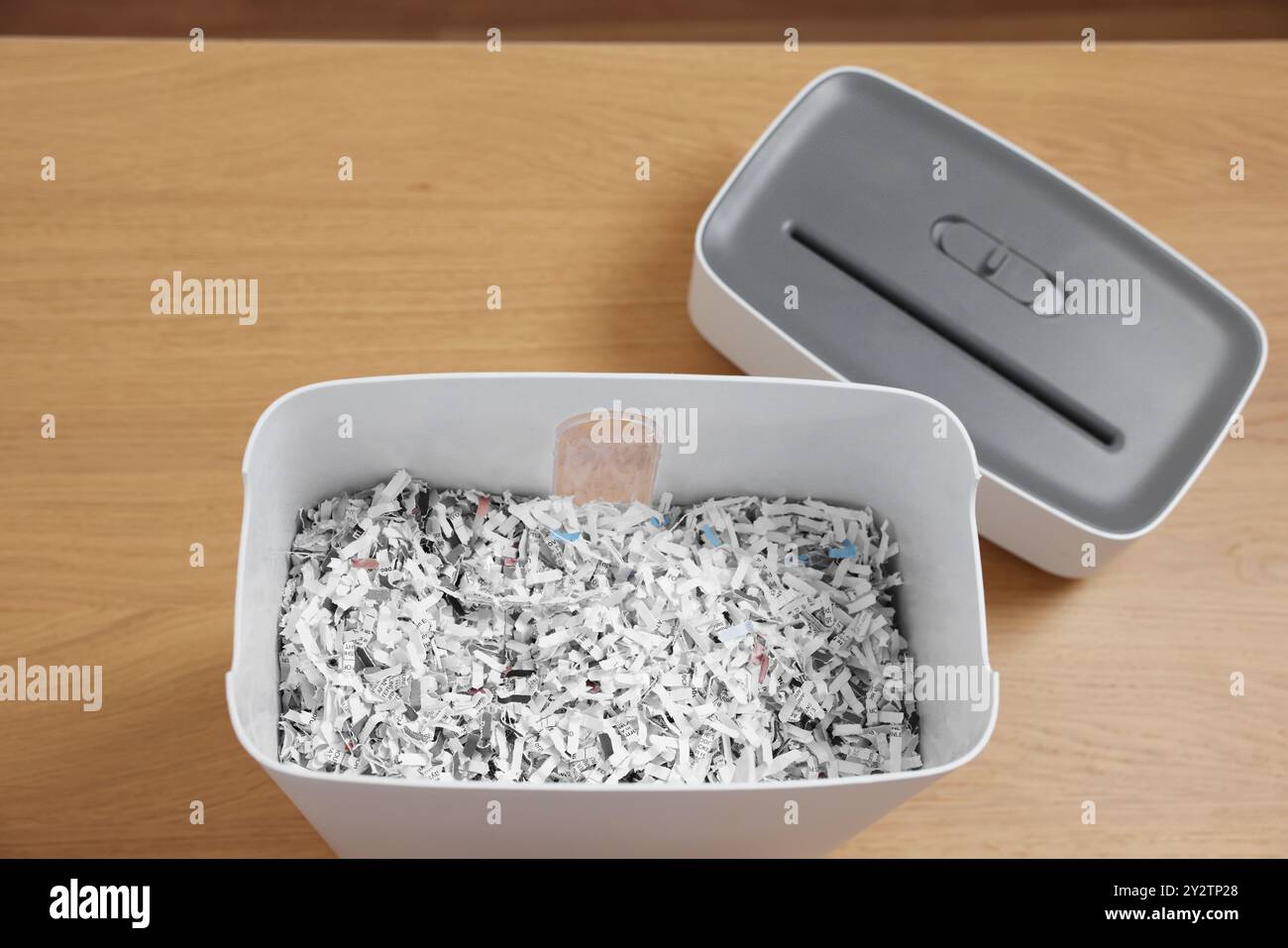 Shredder and basket with paper strips on wooden table, above view Stock ...