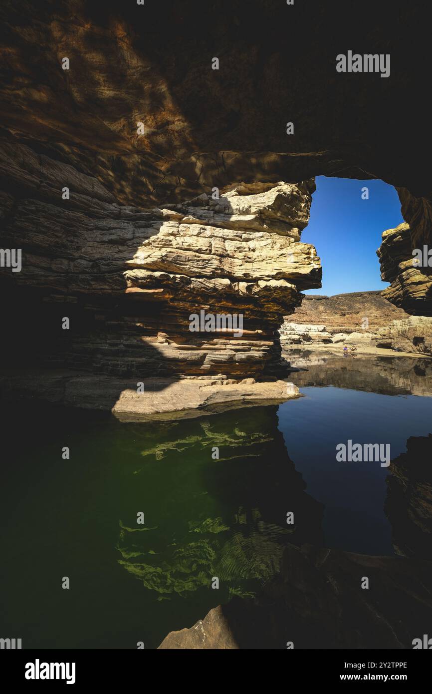 A beautiful natural rock formation with a clear blue sky and reflective ...