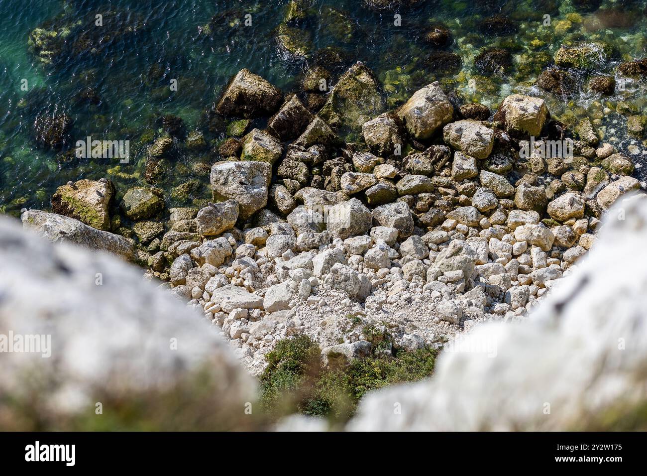 Aerial view of a rocky shoreline with clear blue-green water, showing ...