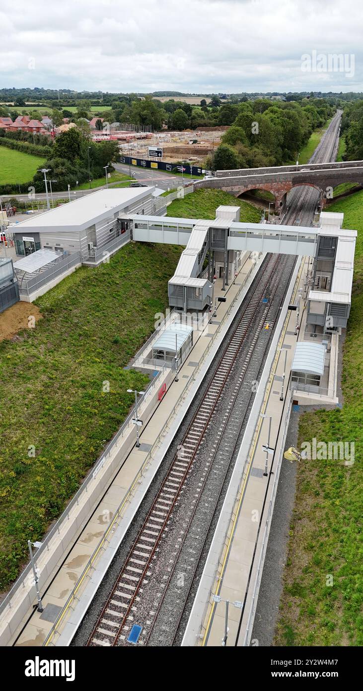 An Aerial view of Winslow railway station with tracks, platforms, and surrounding greenery in a ...