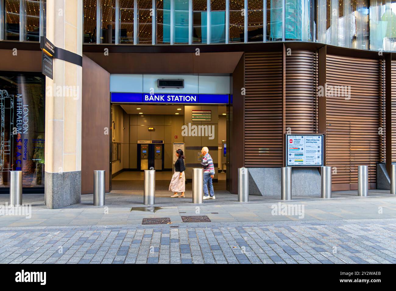 Two people walking past the Walbrook entrance to Bank station located ...
