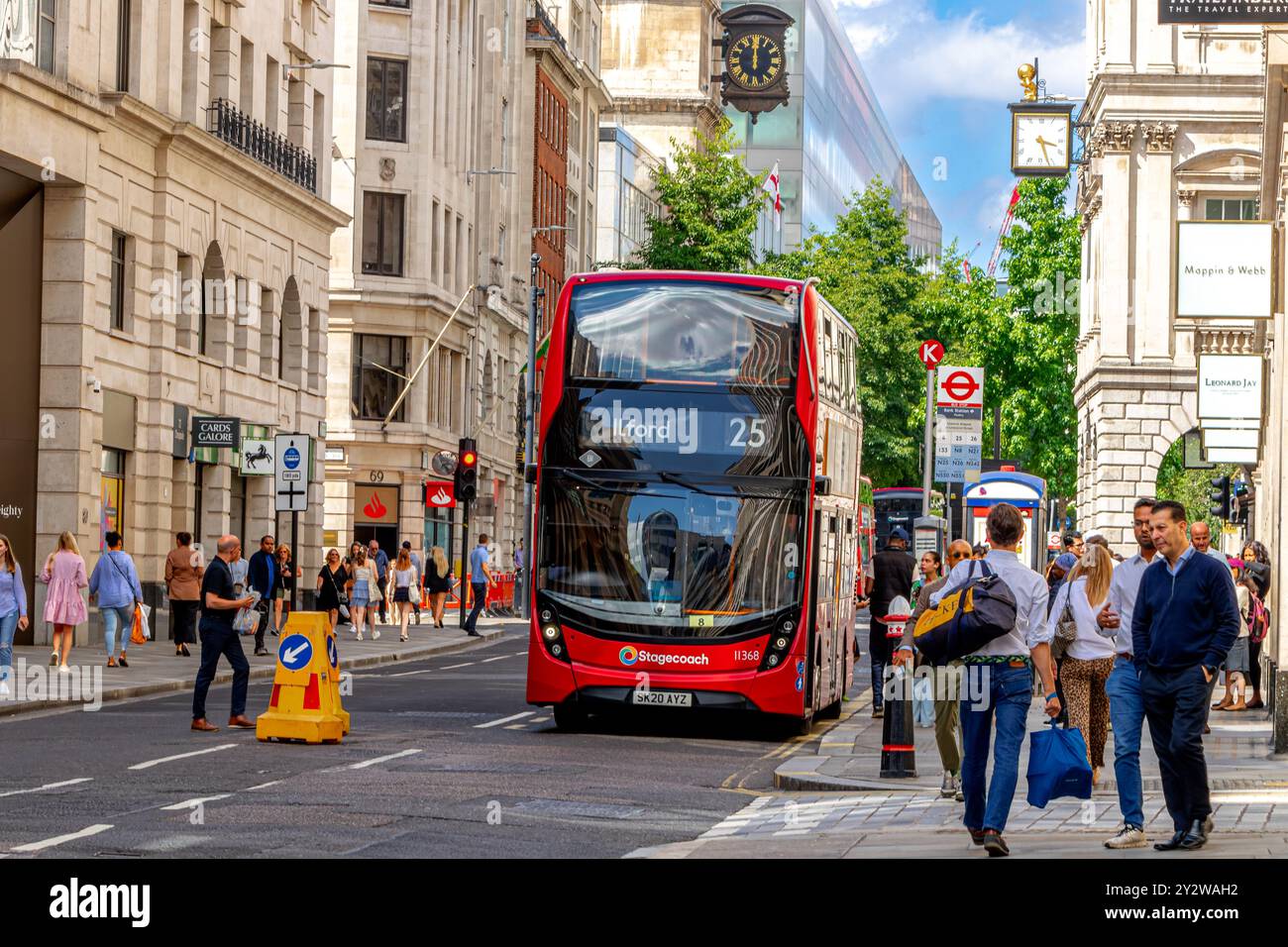 A No 25 red London double decker bus approaches a bus stop on Poultry ...