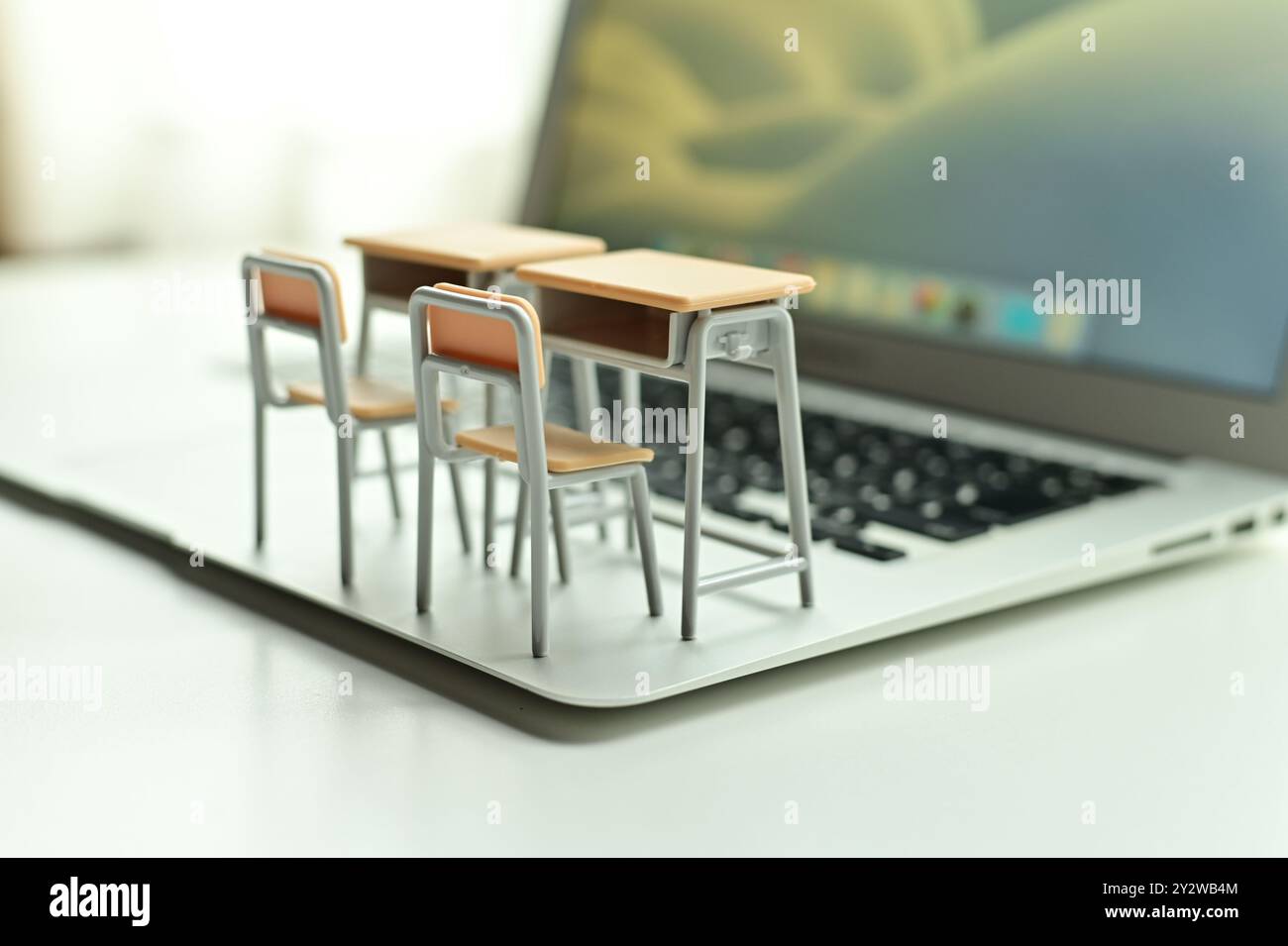 The miniature school desks and chairs on a laptop keyboard representing ...